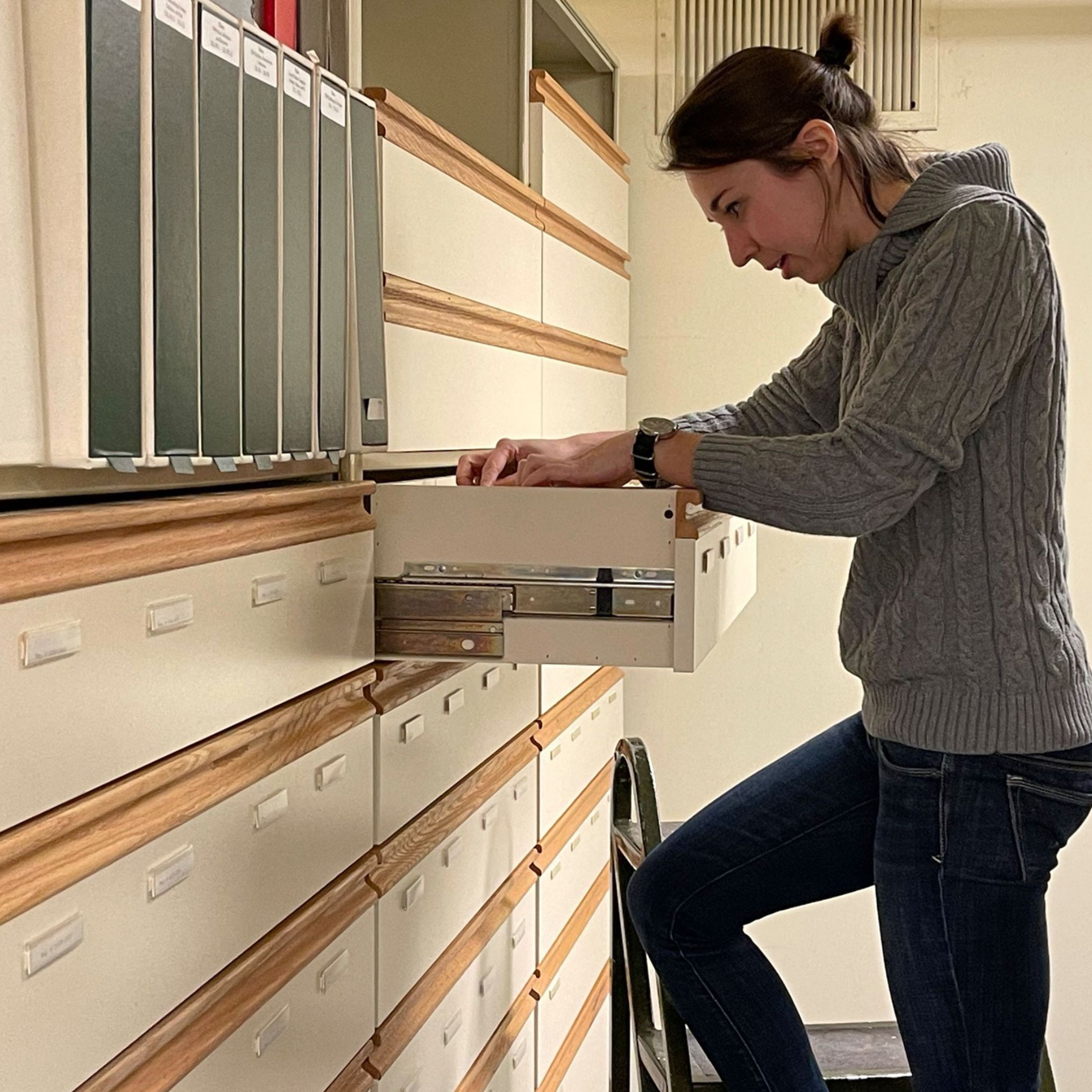 Person working in the OPM Archives surrounded by archival storage shelves